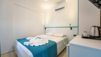 Quarto de hotel com cama, cafeteira e ar condicionado.