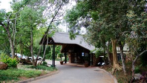 Uma entrada coberta para um edifício, rodeado por árvores e vegetação.