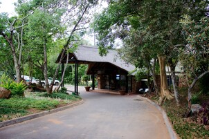 Uma entrada coberta para um edifício, rodeado por árvores e vegetação.