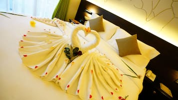 Cama bem arrumada com arranjo de toalha em formato de cisne e flores espalhadas.