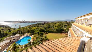 Área de piscina no terraço com vista para o mar e para a paisagem urbana.