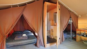 Quarto com tenda, uma cama, uma mesinha e uma prateleira com objetos.