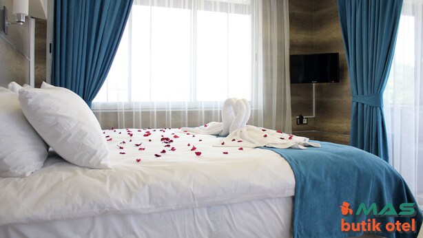 Quarto de hotel com cama, cortinas azuis, televisão e TV montada na parede.