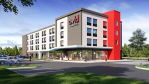 Um hotel moderno com fachada em vermelho e cinza, vários andares e uma área de estar externa coberta.