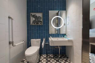 Casa de banho moderna com sanita, lavatório e barra de apoio.