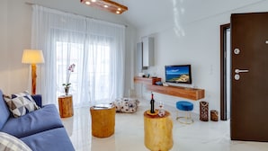 Uma sala de estar moderna com sofá, mesa de centro e televisão sobre um suporte de madeira.