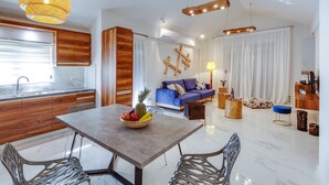 Uma sala de estar moderna com uma mesa de jantar, sofá e uma cozinha com armários de madeira.