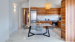Cozinha moderna com armários de madeira, bancada de mármore e área de jantar com mesa e cadeiras.