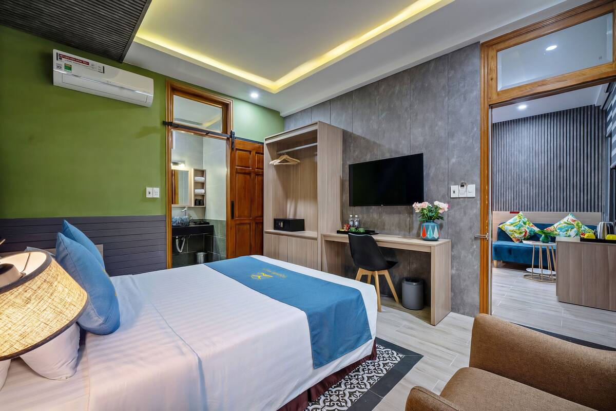 Quarto de hotel com cama, escrivaninha e televisão.