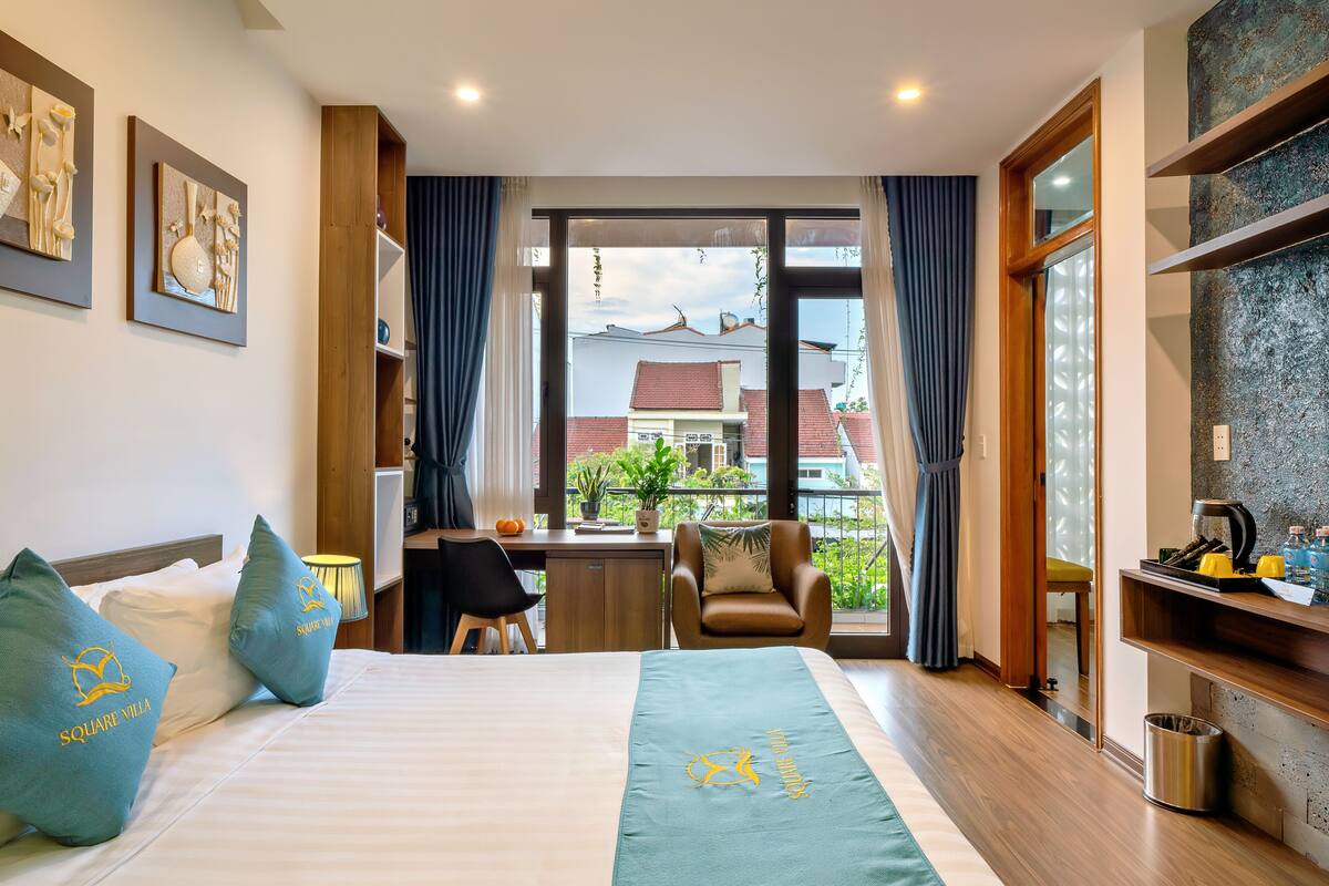 Quarto de hotel com uma cama, uma mesa, uma cadeira e vista para o exterior.