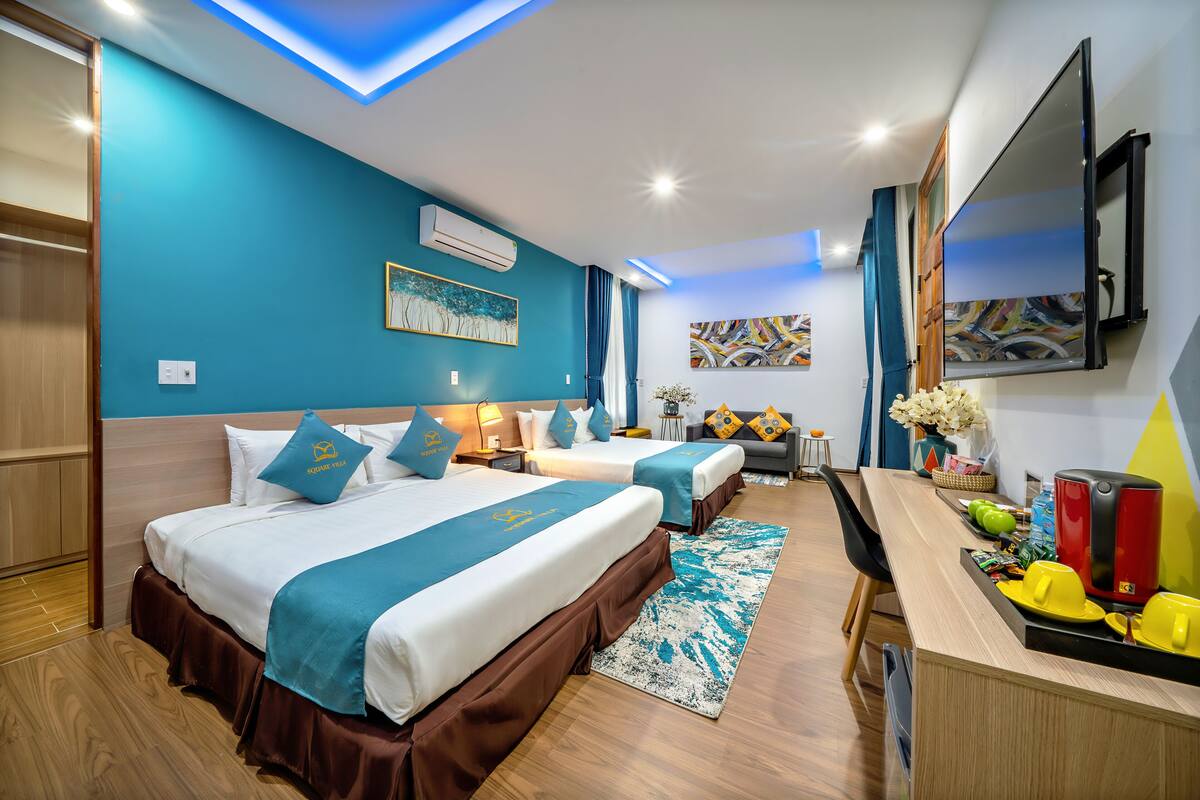 Quarto de hotel moderno com duas camas, uma escrivaninha, uma TV e um banheiro.