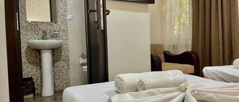 Quarto de hotel com cama, televisão na parede, pia e espelho.