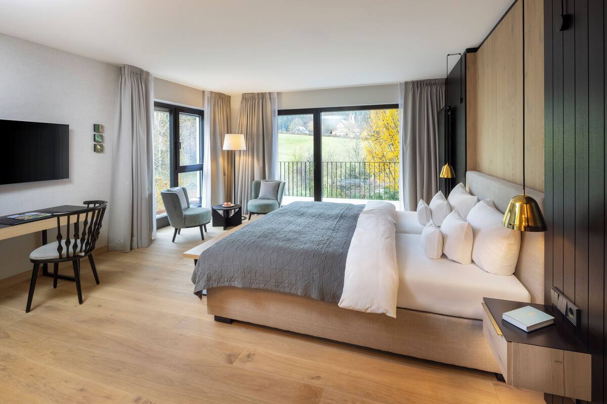 Quarto de hotel moderno com uma cama grande, uma escrivaninha e uma televisão.
