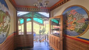 Um corredor com murais tradicionais, uma porta de madeira e vista para um jardim.