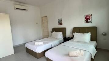Quarto de hotel com duas camas, um guarda-roupa e uma porta.