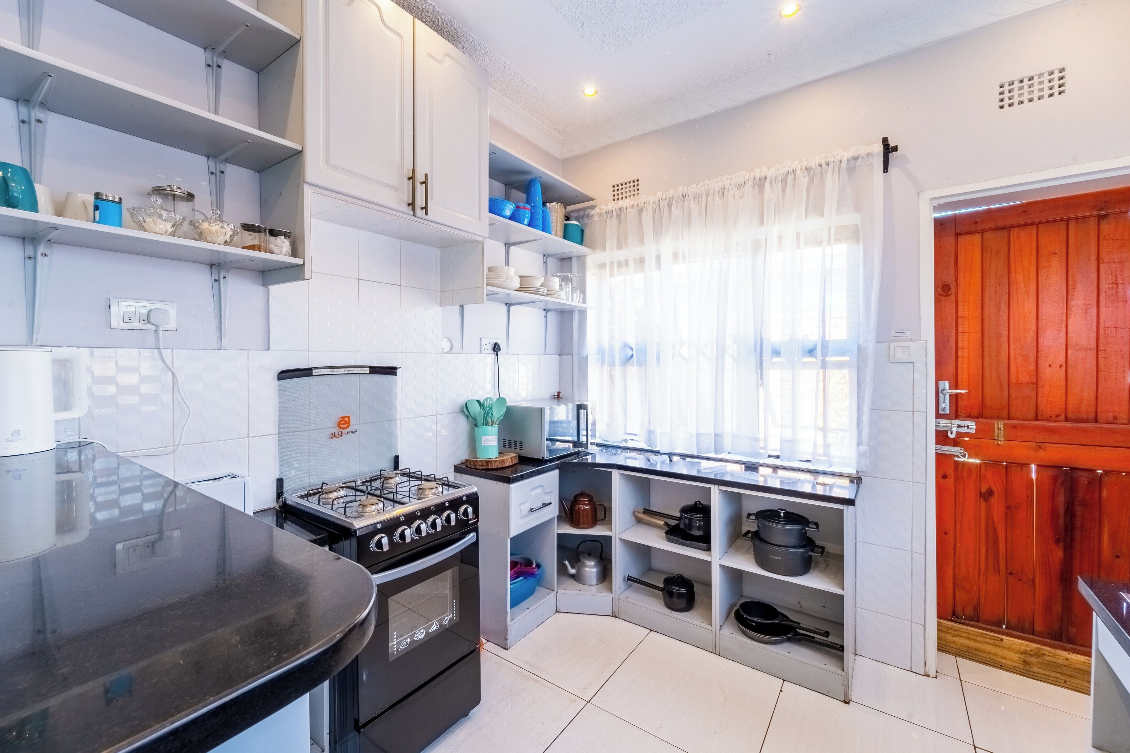 Uma cozinha compacta com armários brancos, bancada preta e fogão a gás.