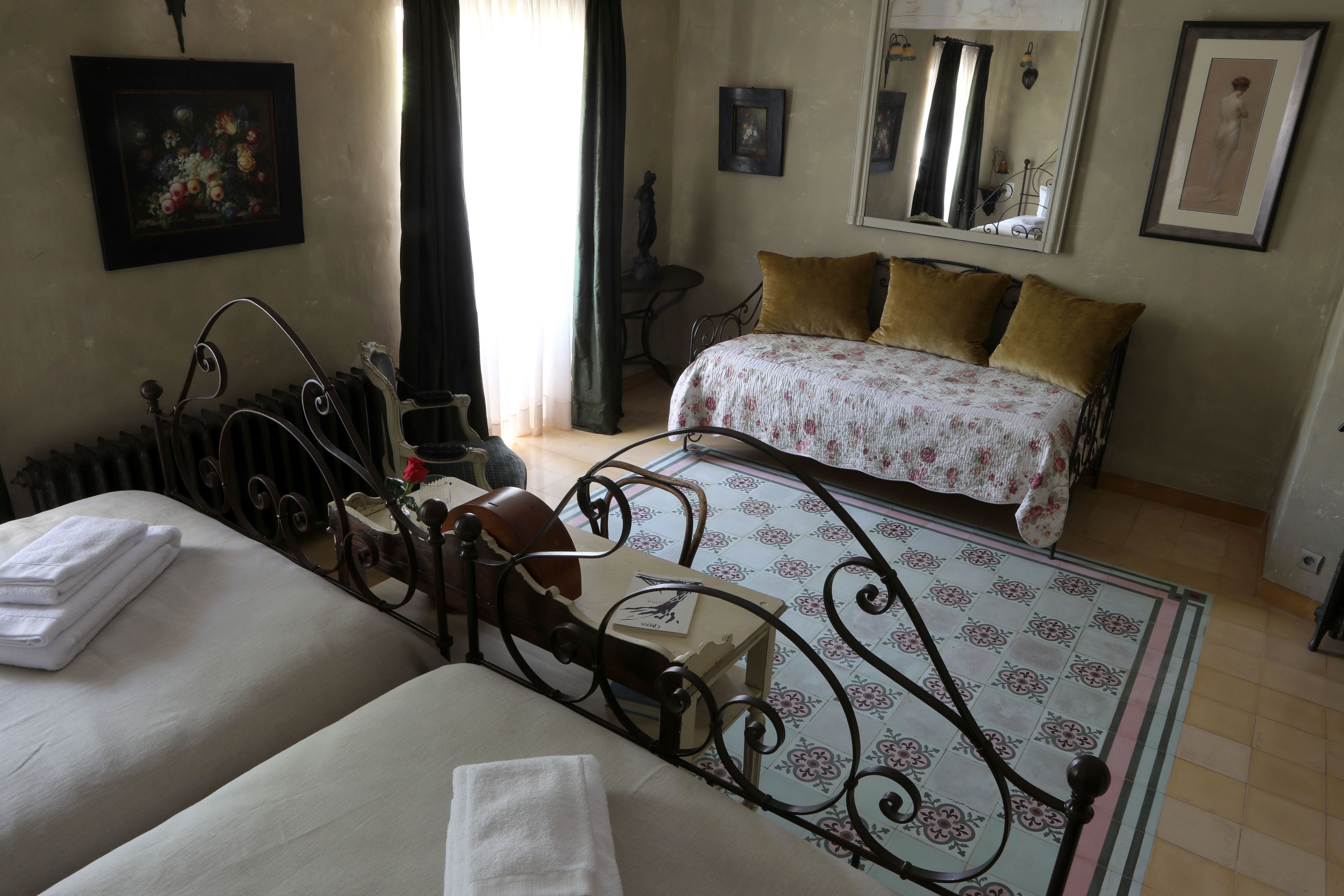 Quarto com duas camas, um radiador, uma mesinha e um espelho.