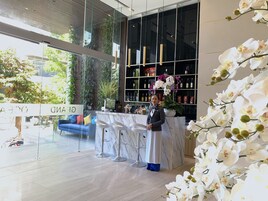 Uma área de bar moderna com balcão de mármore, banquetas e uma grande janela com vista para o horizonte da cidade.