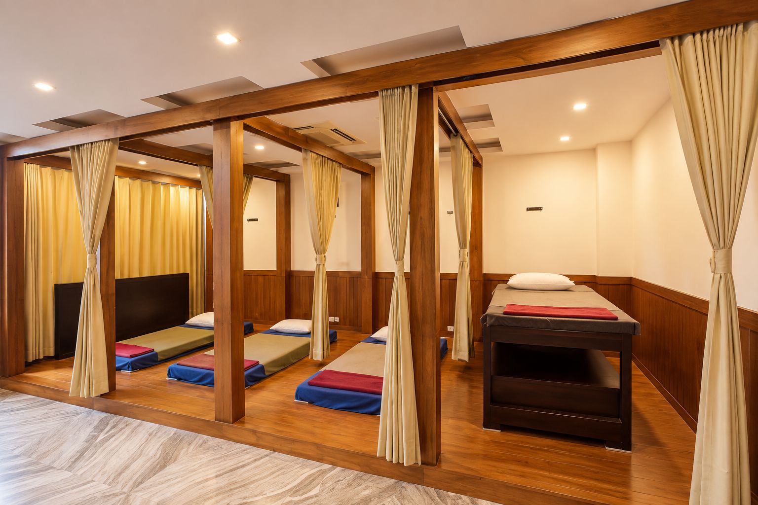 Quarto com quatro camas dispostas em linha, cada uma com cabeceira de madeira e um colchão.