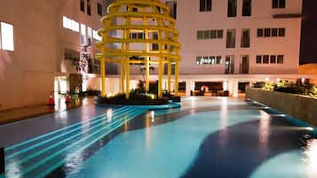 Uma área de piscina com uma estrutura amarela, rodeada por um edifício com várias janelas.