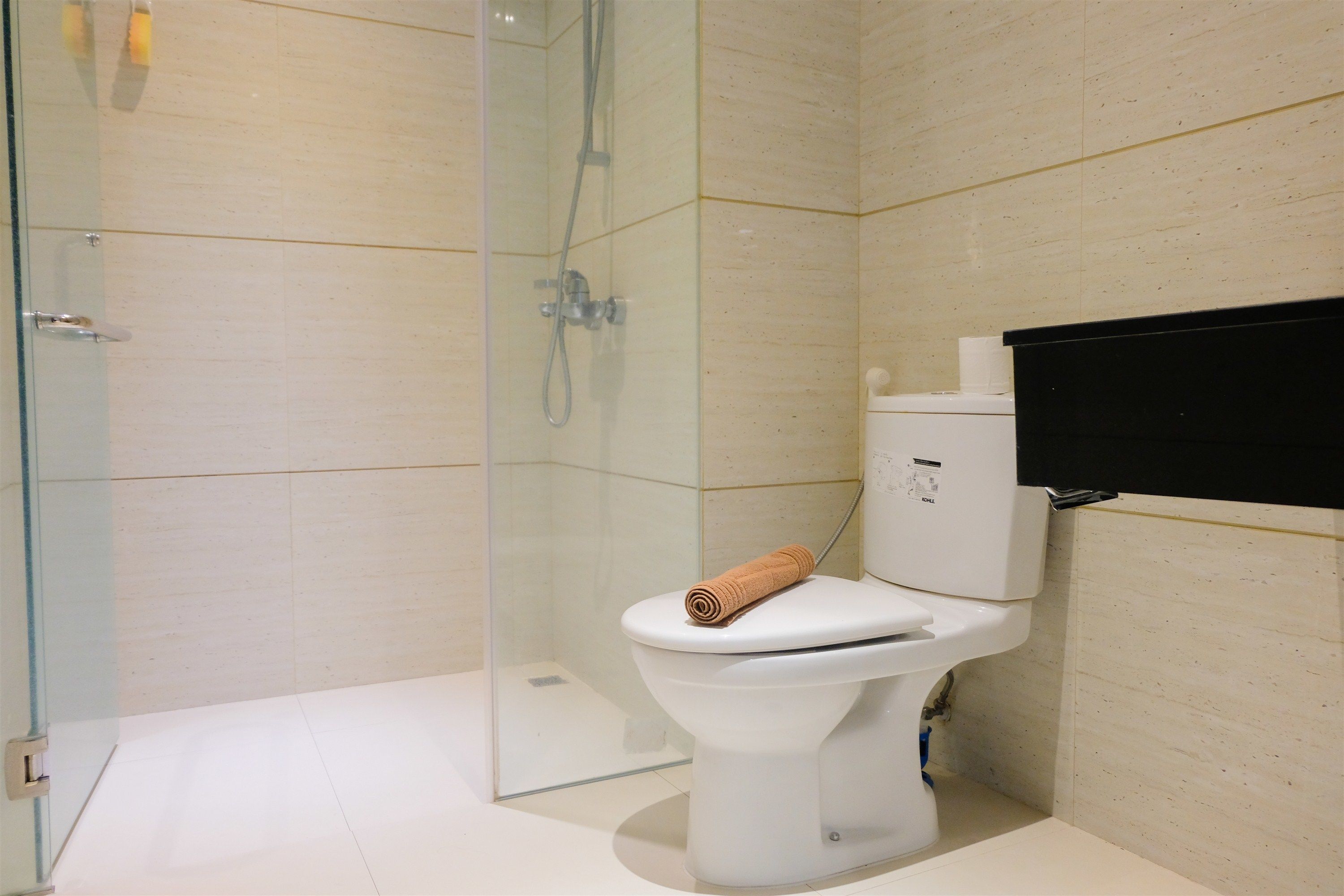 Uma casa de banho moderna com cabine de duche em vidro, sanita branca e espelho de barbear preto.
