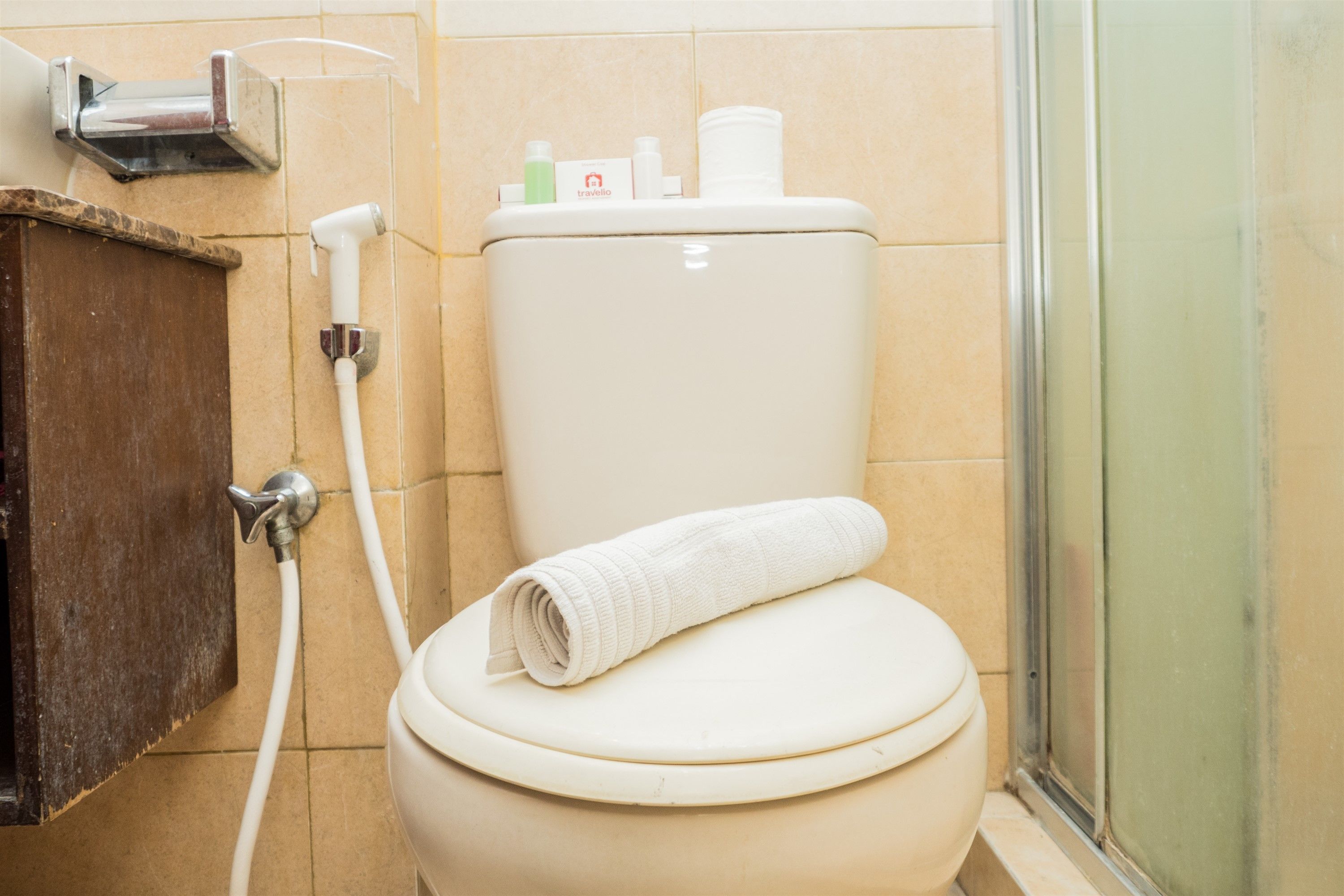 Sanitário com toalha, chuveiro e armário.
