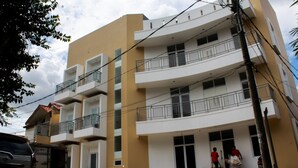 Um edifício de vários andares com varandas, uma caminhonete estacionada e uma motocicleta.