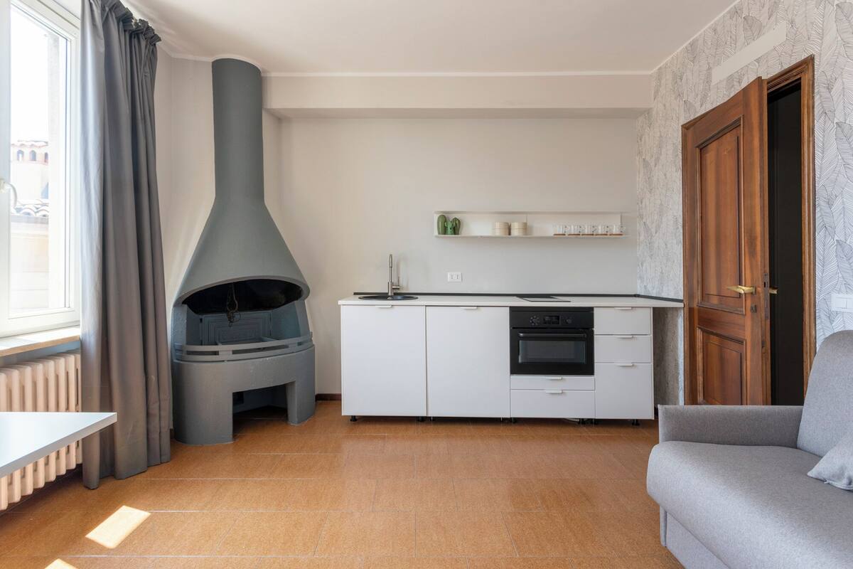 Uma cozinha compacta com fogão moderno, armários brancos e forno embutido.