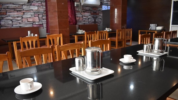 Restaurante com balcão preto, xícaras brancas e chaleiras de café de aço inoxidável.