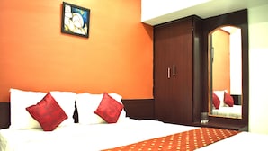 Quarto de hotel com uma cama, um espelho grande e uma porta.