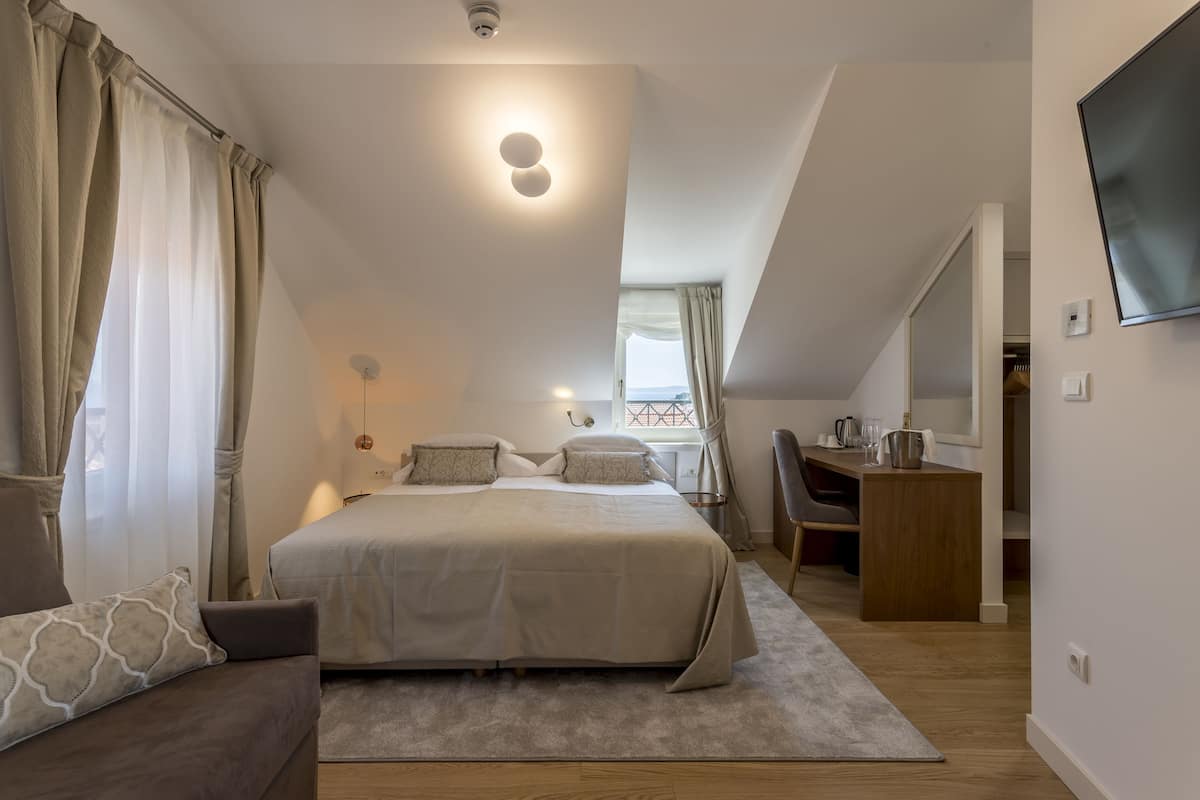 Quarto moderno com cama grande, escrivaninha e vista da cidade.