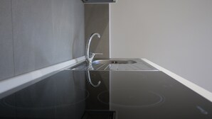 Uma cozinha moderna com bancada preta elegante, torneira de aço inoxidável e forno embutido.