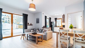Uma sala de estar moderna com sofá, mesa de centro e área de jantar.