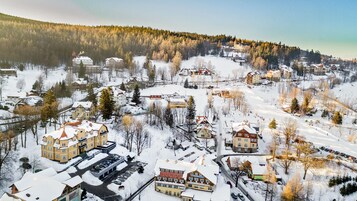 Uma cidade coberta de neve com diversos edifícios, incluindo um hotel com vários andares e uma área de estacionamento.