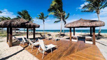Na praia, praia de areia branca, espreguiçadeiras, guarda-sóis de praia