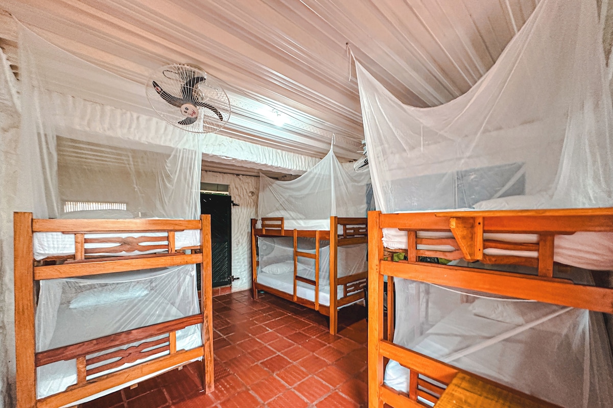 Quarto com beliches, mosquiteiros e ventilador de teto.