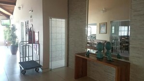 Um hall amplo com um espelho grande, um aparador de madeira e um carrinho de metal.