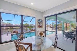 Uma área de piscina interior moderna com paredes de vidro, uma mesa redonda de vidro e cadeiras.