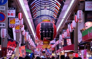 Uma rua movimentada com lanternas japonesas tradicionais e placas.