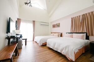 Quarto de hotel com duas camas, uma escrivaninha com computador, um banco e um candeeiro de teto.