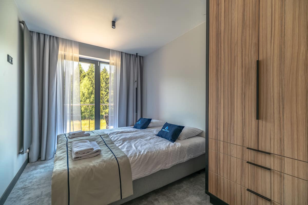 Quarto com cama grande, guarda-roupa e janela com cortinas.