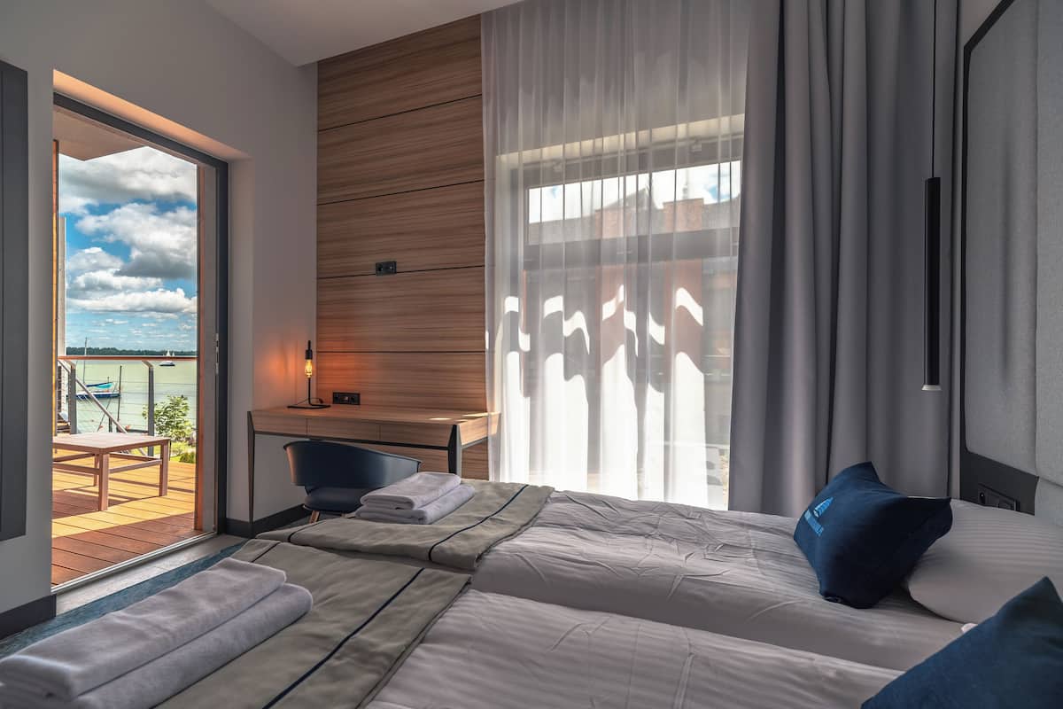 Quarto de hotel moderno com uma cama grande, uma escrivaninha e vista para o exterior.