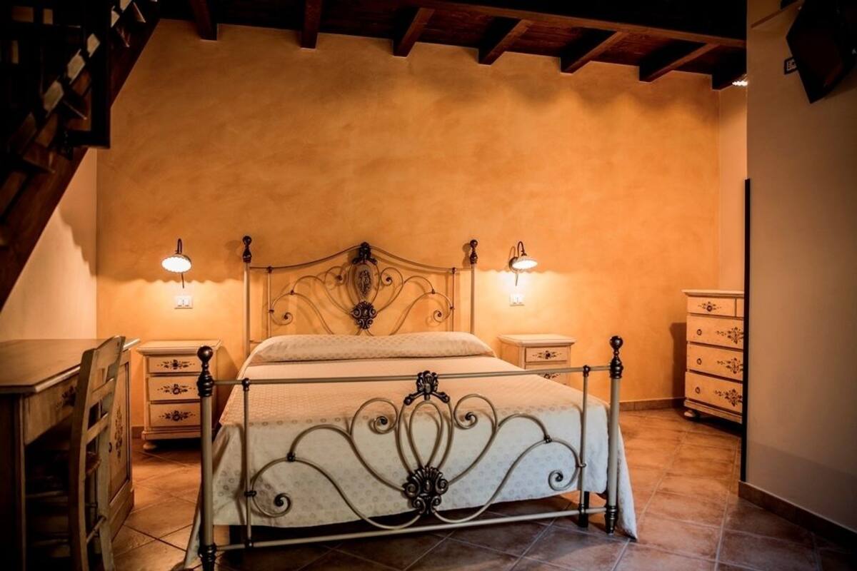 Quarto com cama, duas mesinhas de cabeceira, cômoda e escada.