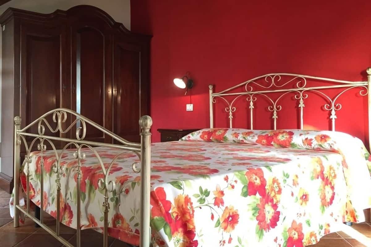 Quarto com cama, guarda-roupa de madeira e parede vermelha.