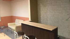 Um quarto com uma receção de madeira, duas cadeiras, um sofá e uma parede com padrão de tijolos.