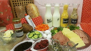 Diversos alimentos como pão, queijo, carnes e acompanhamentos dispostos sobre uma mesa.