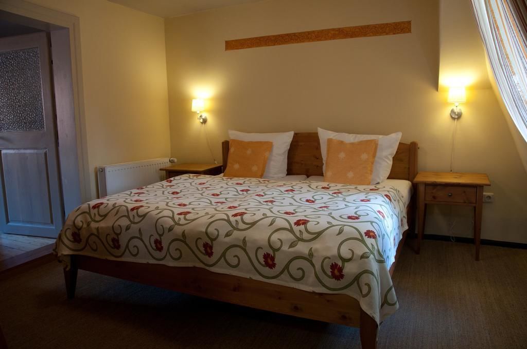Quarto com uma cama, duas mesas de cabeceira e duas luminárias fixadas na parede.