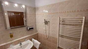 Uma casa de banho com lavatório, espelho, porta-toalhas e um secador de toalhas.