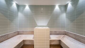 Um banheiro moderno com pia central, paredes revestidas de azulejos e bancadas de granito.