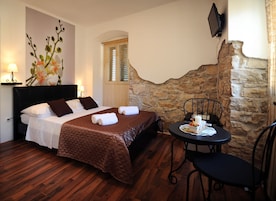 Quarto de hotel com cama, mesa com vela e parede de pedra.